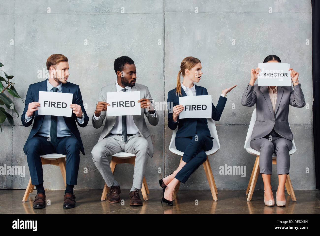 multiethnic businesspeople holding cards with 'fired' and 'director ...