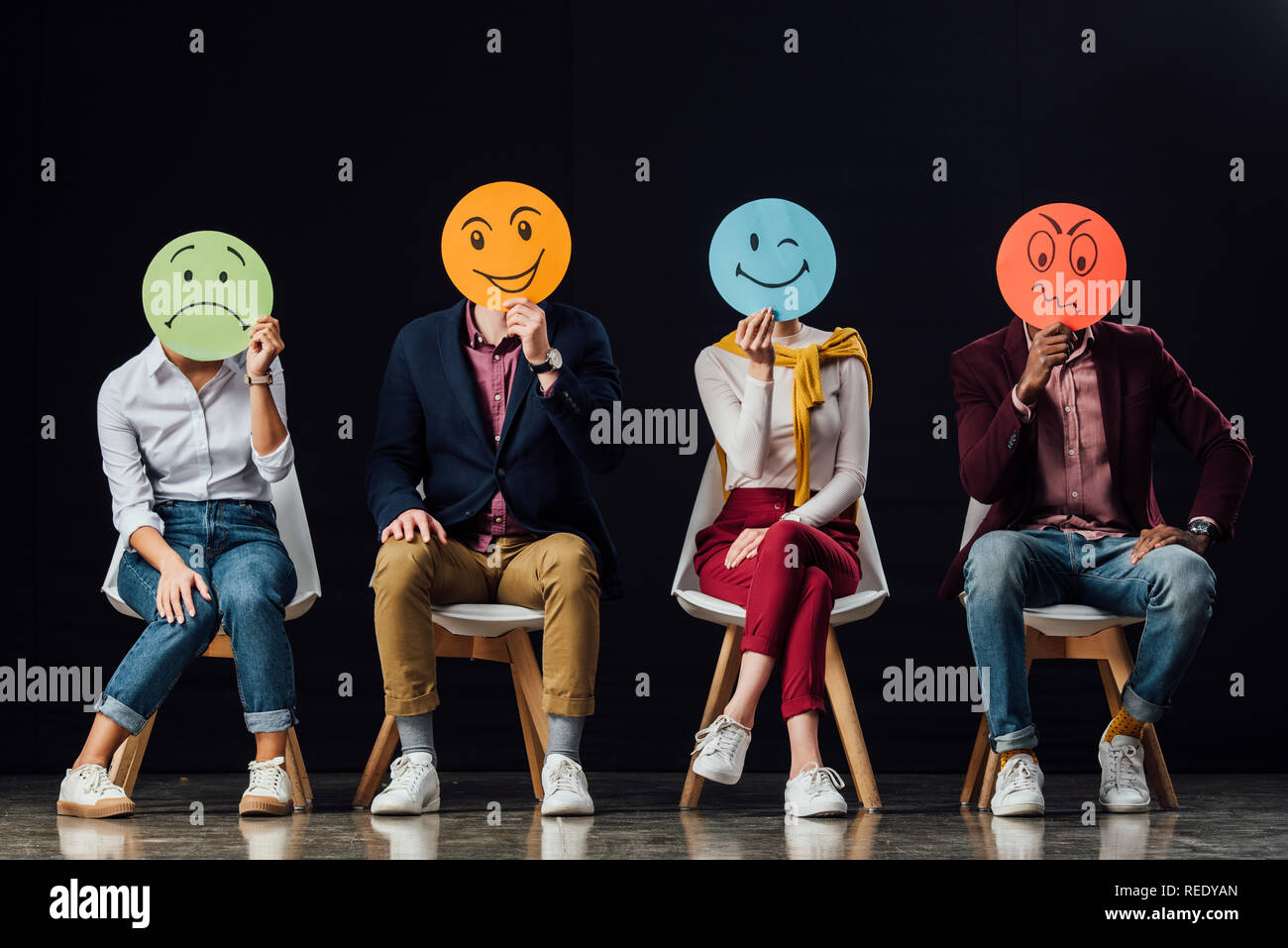 group of people sitting on chairs and holding face cards with various ...