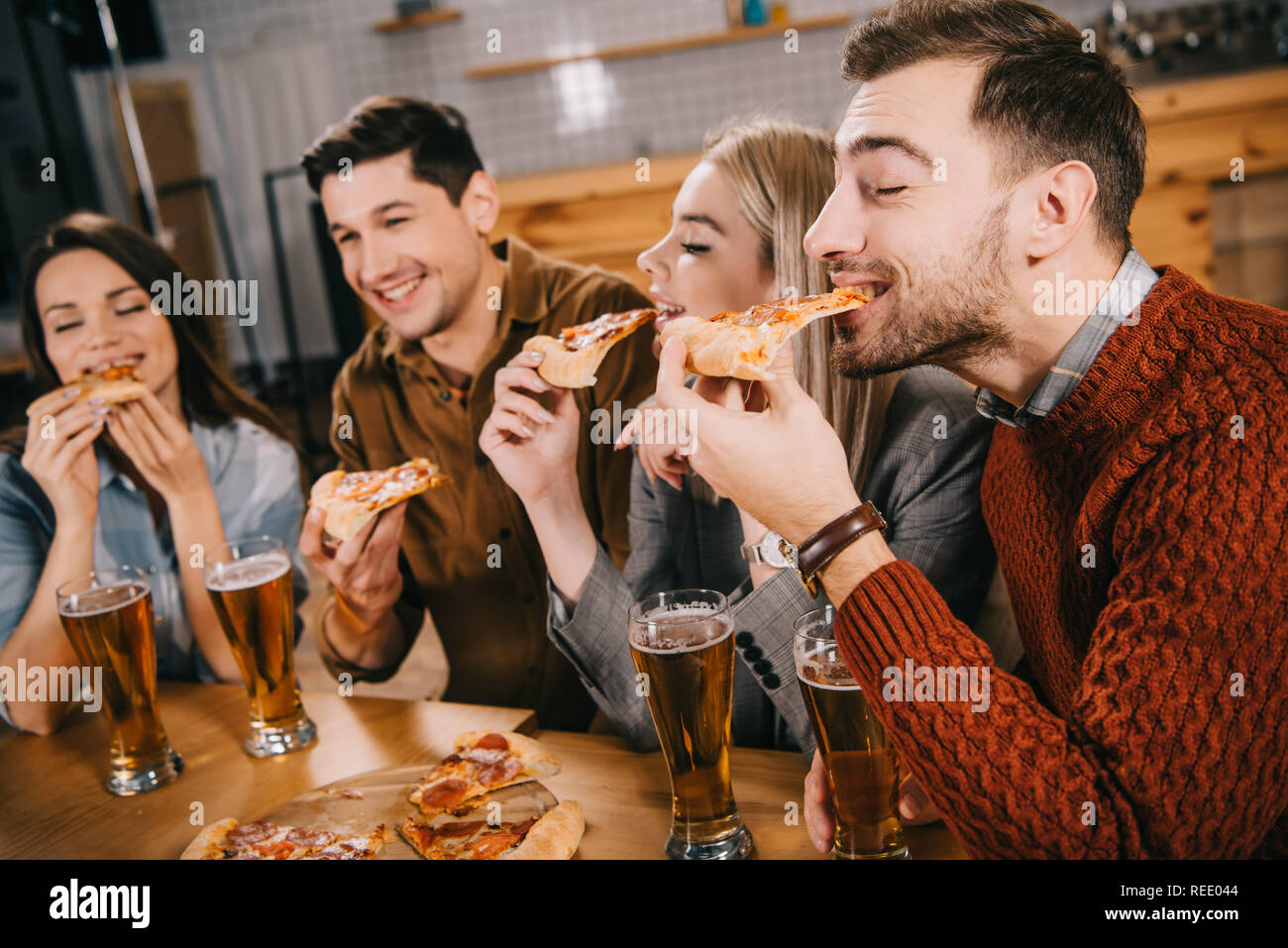 selective focus of happy friends eating pizza in bar Stock Photo - Alamy