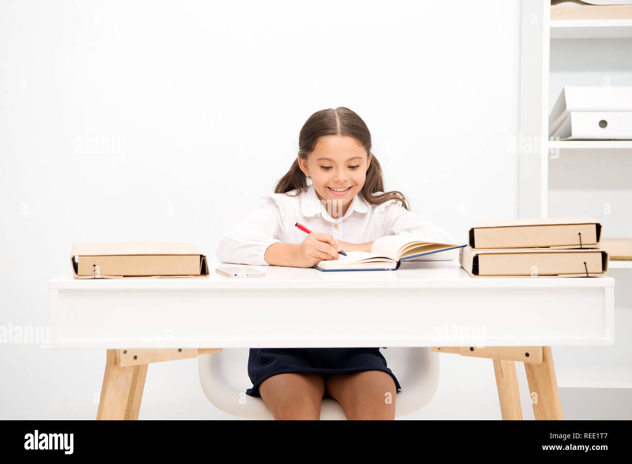 Excellent pupil. Girl child writes hometask while sit table white ...
