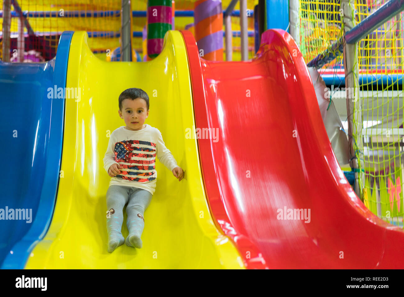 Little boy is going down a slide at the playground. He is laughing and ...