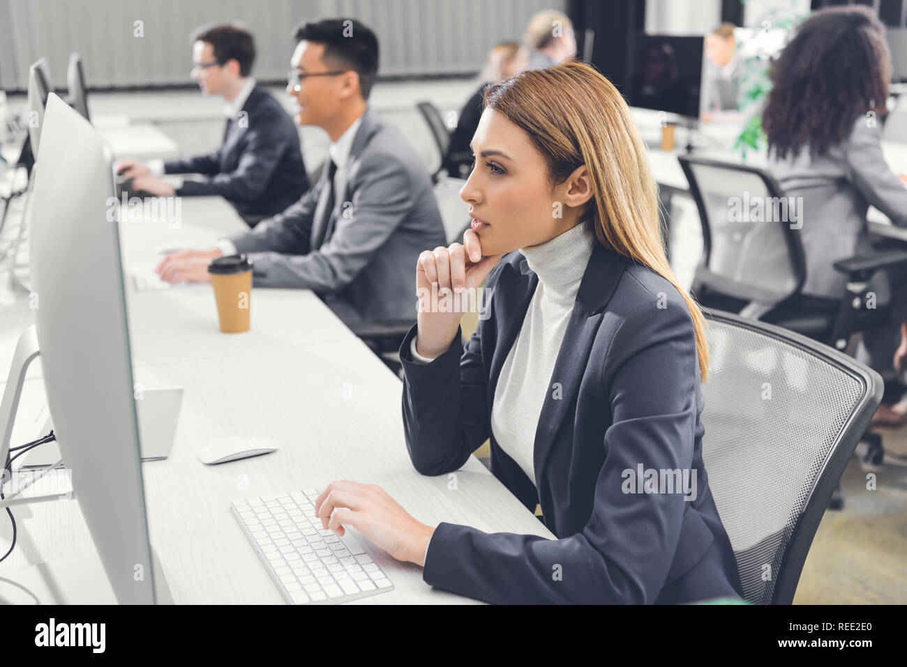 concentrated young businesswoman using desktop computer while working ...