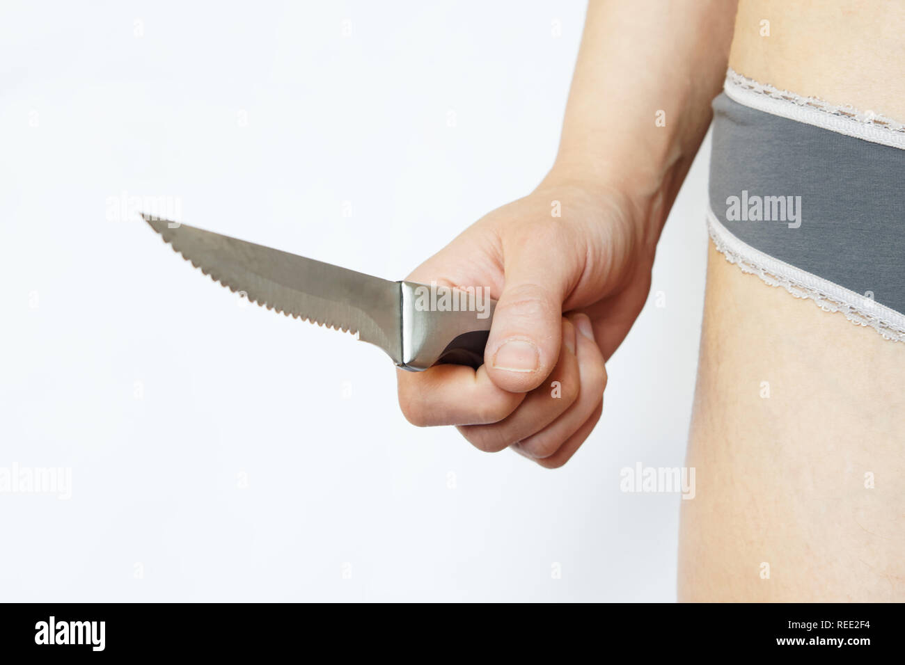 Female hand holds a sharp knife on a white background. The problem of ...