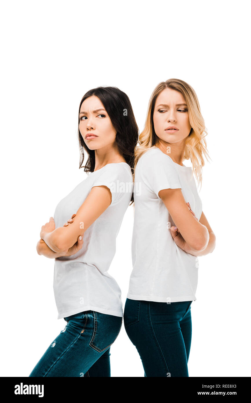 side view of upset young women standing back to back with crossed arms ...