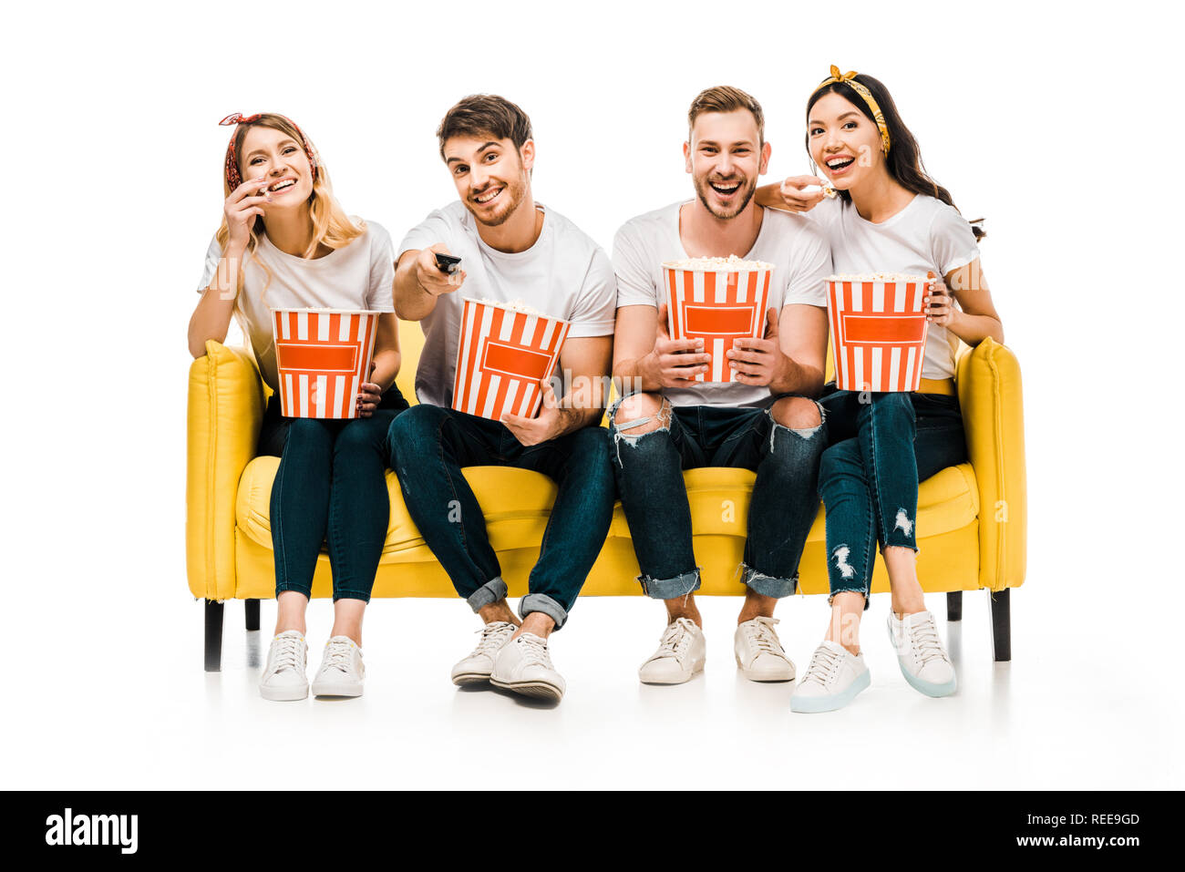 happy young friends holding popcorn boxes and watching tv while sitting ...