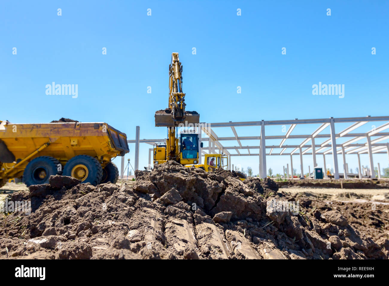 Big excavator is filling a dumper truck with soil at construction site ...