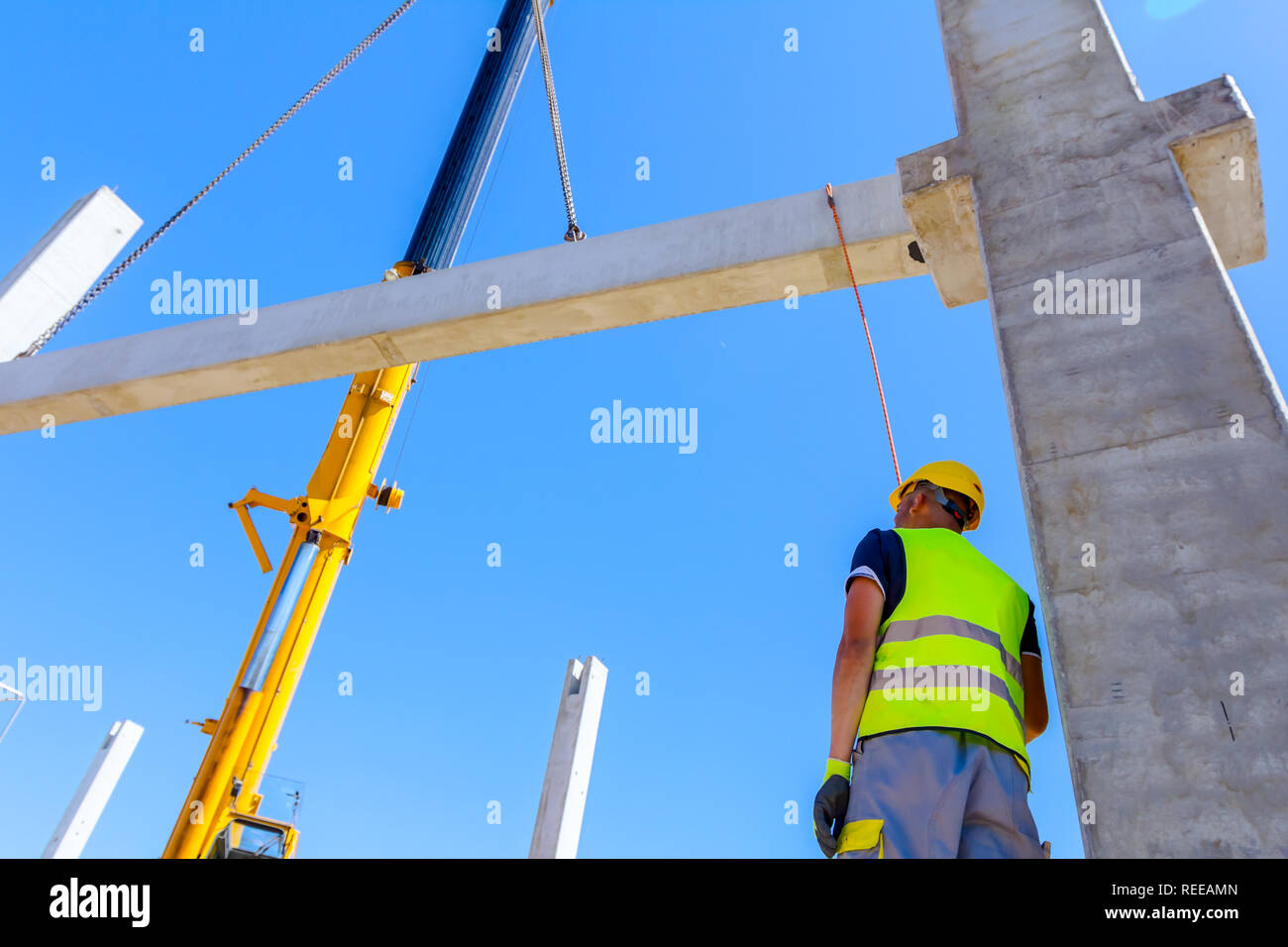 Worker is helping mobile crane with rope to manage concrete joist for ...