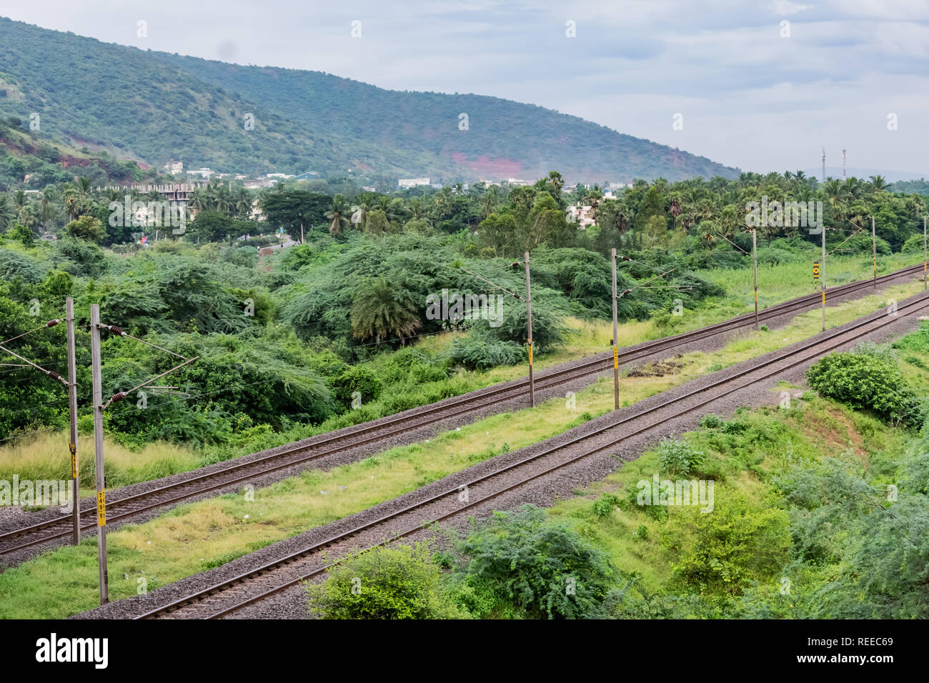 straight railway track goes to horizon in green landscape under blue ...