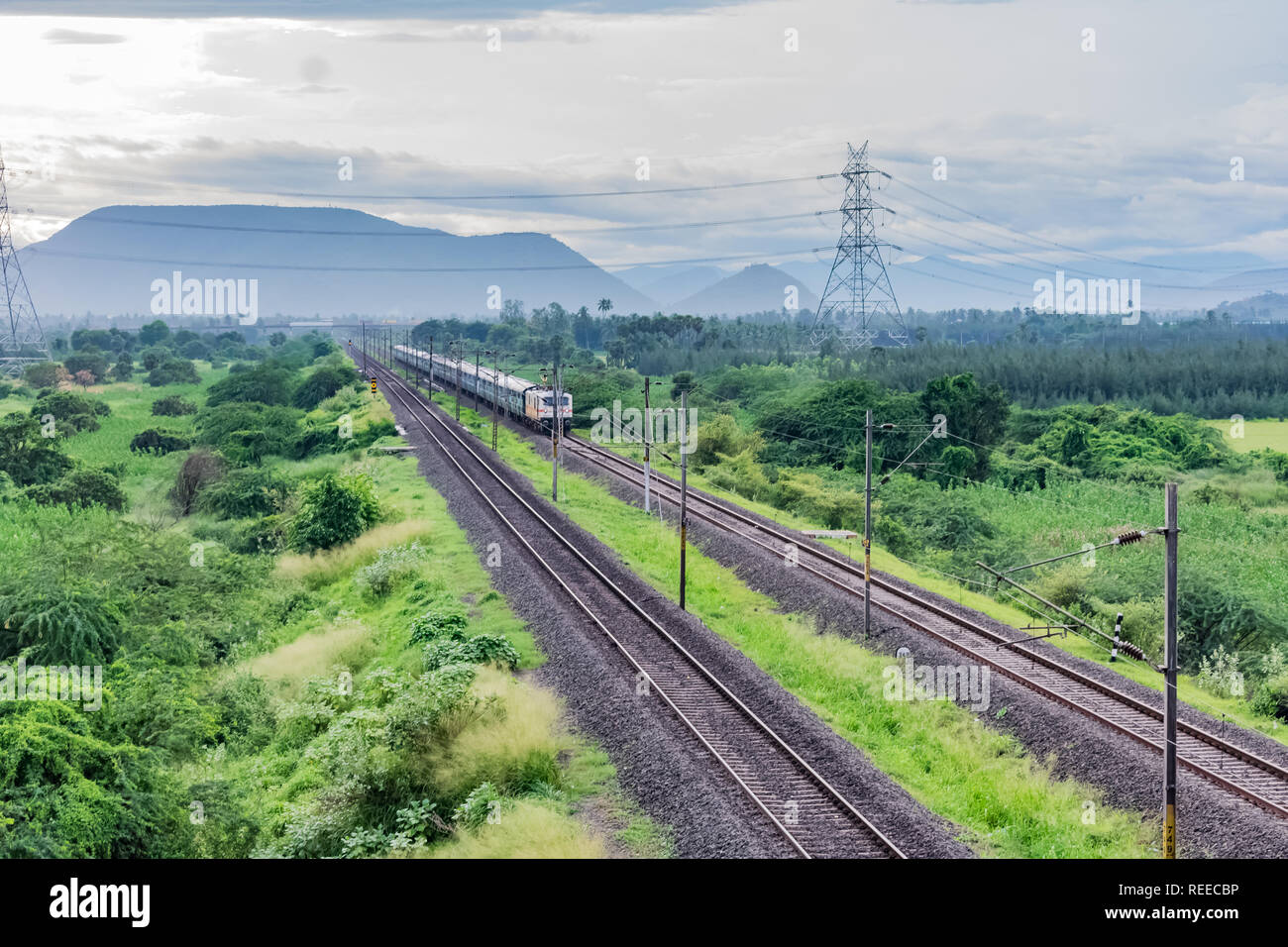 straight railway track goes to the horizon in the green landscape under ...