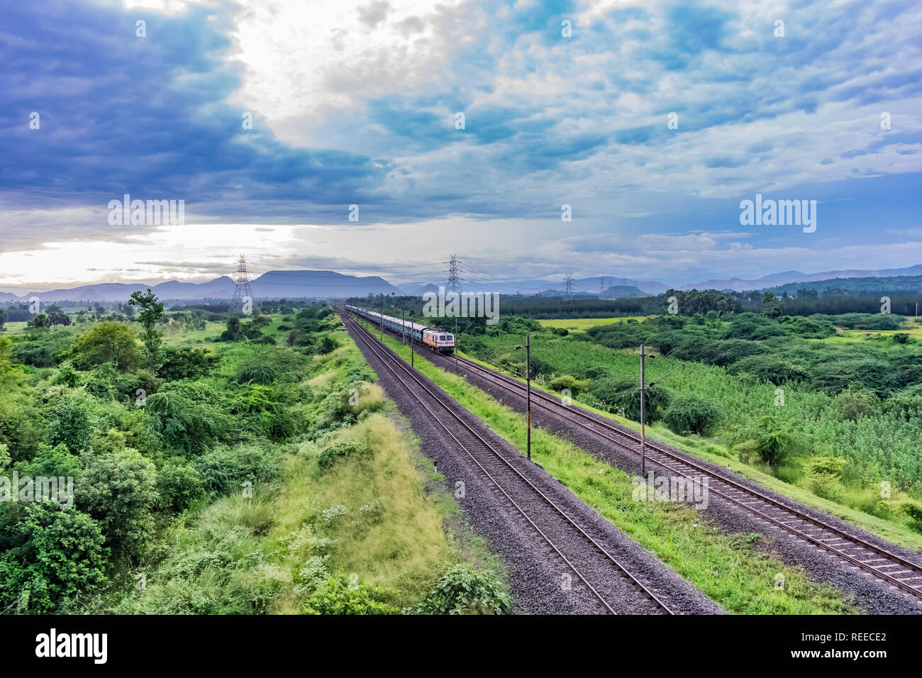 straight railway track goes to the horizon in the green landscape under ...
