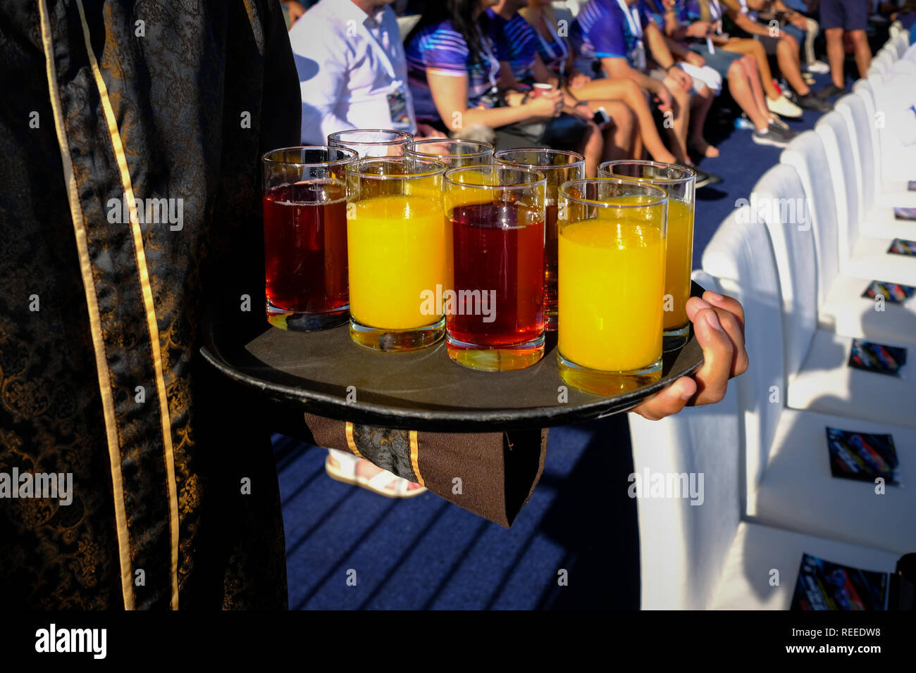 A waiter serving orange and Pomegranate juices to VIP spectators Stock ...