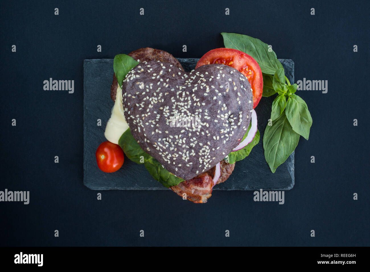 Heart shaped black hamburger on stone plate, love burger fast food ...