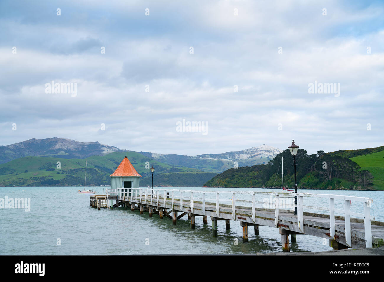 Daly's Wharf or Akaroa jetty in Akaroa Harbor with shed and orange ...