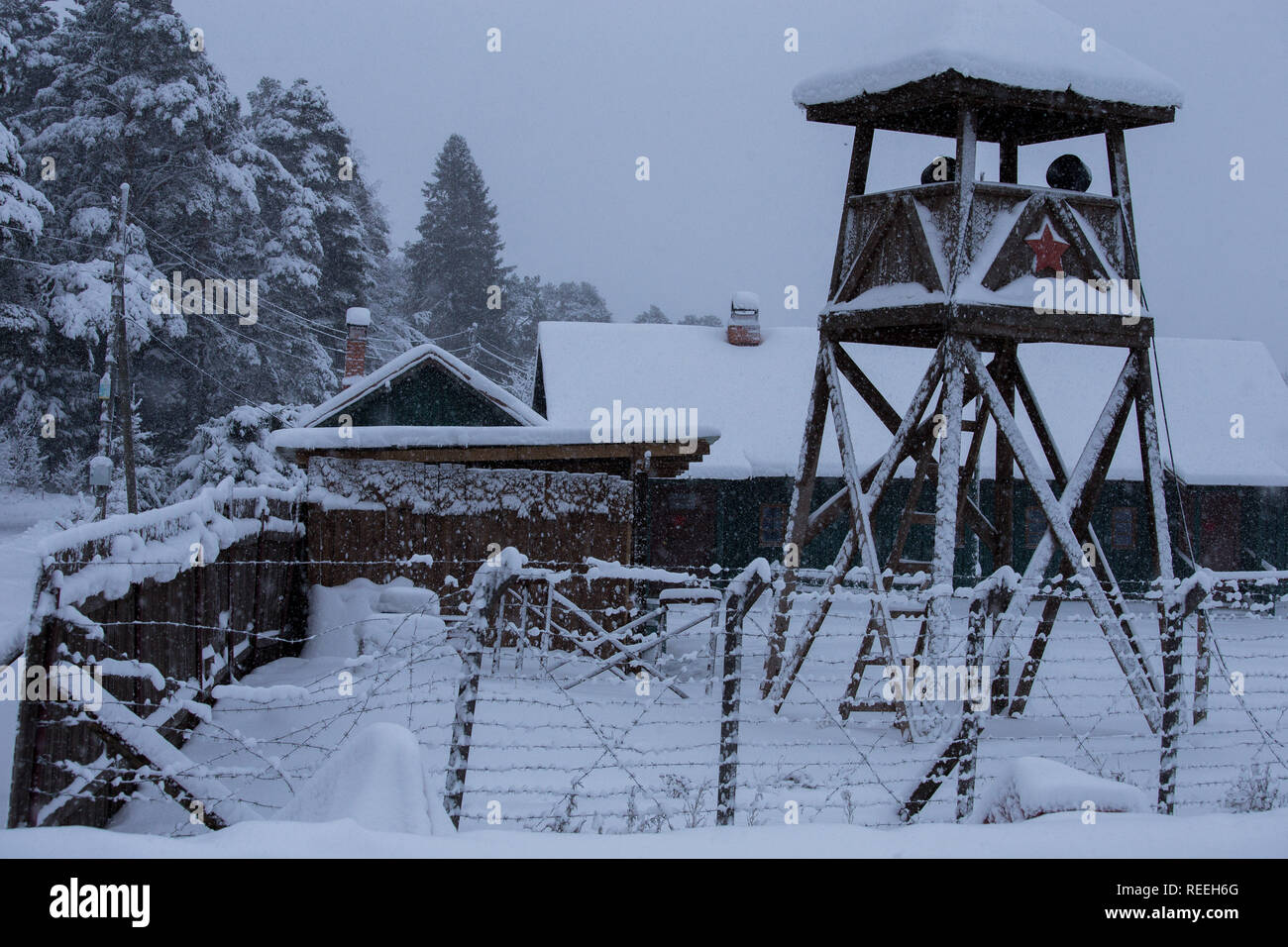 A watchtower with the fence in the middle of the snow covered forest ...