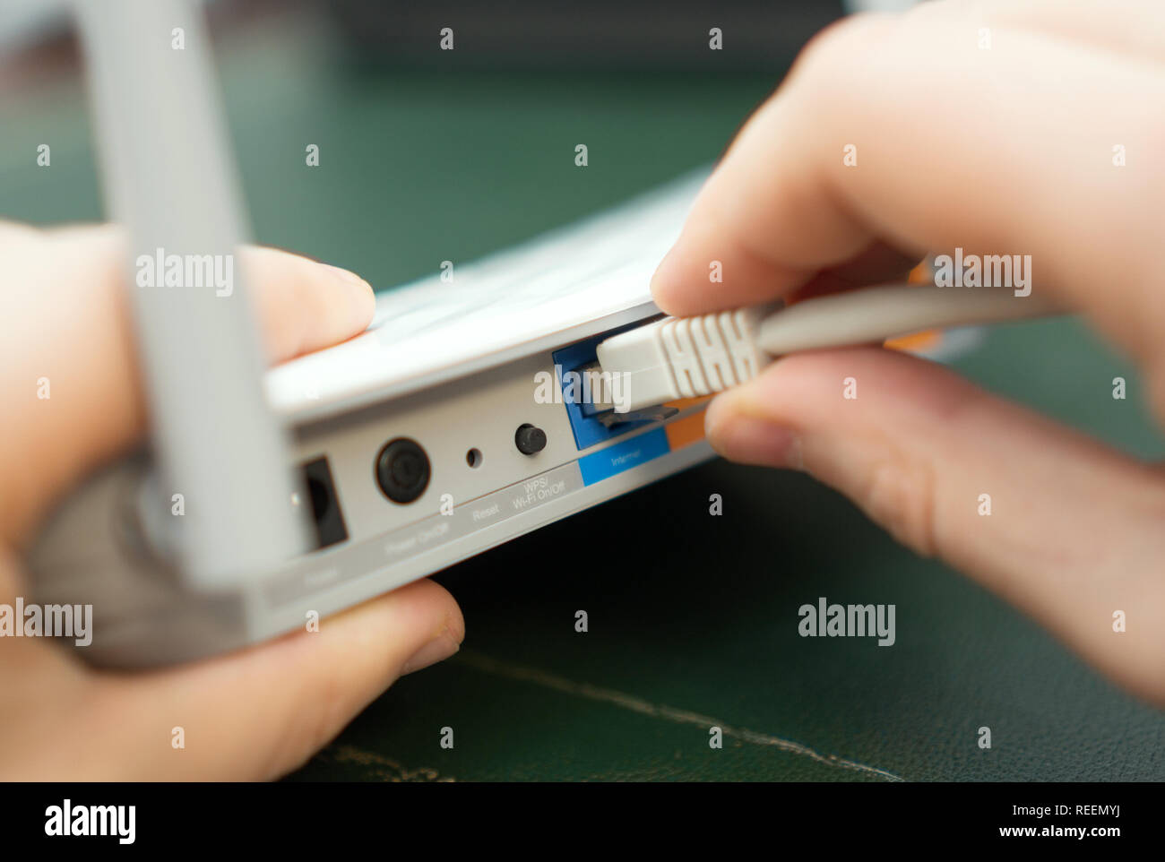 Man plugging internet cable into wifi router Stock Photo - Alamy
