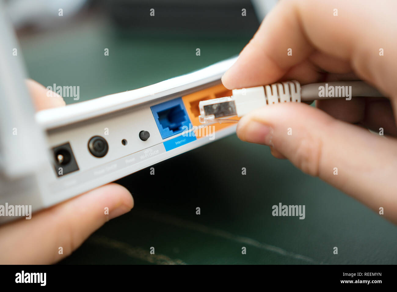 Man plugging internet cable into wifi router Stock Photo - Alamy