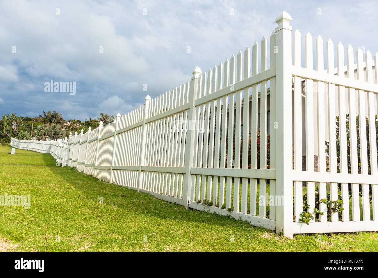 White boundary vertical slat plastic pvc fence along roadside grass ...