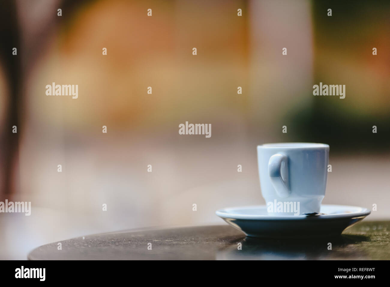 Empty white coffee cup on the wooden table of an outdoor bar, negative ...