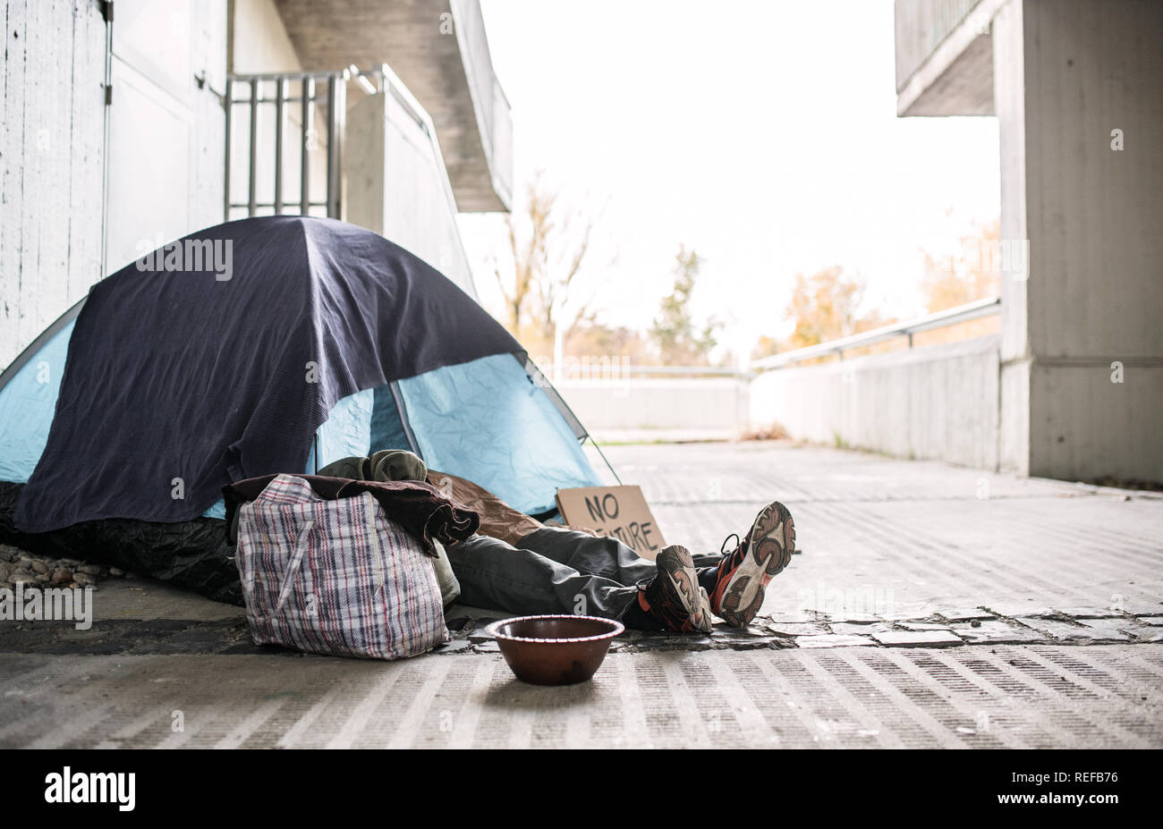 Legs and feet of homeless beggar man lying on the ground in city ...