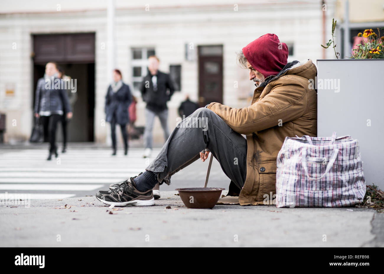 Homeless beggar man sitting outdoors in city asking for money donation ...