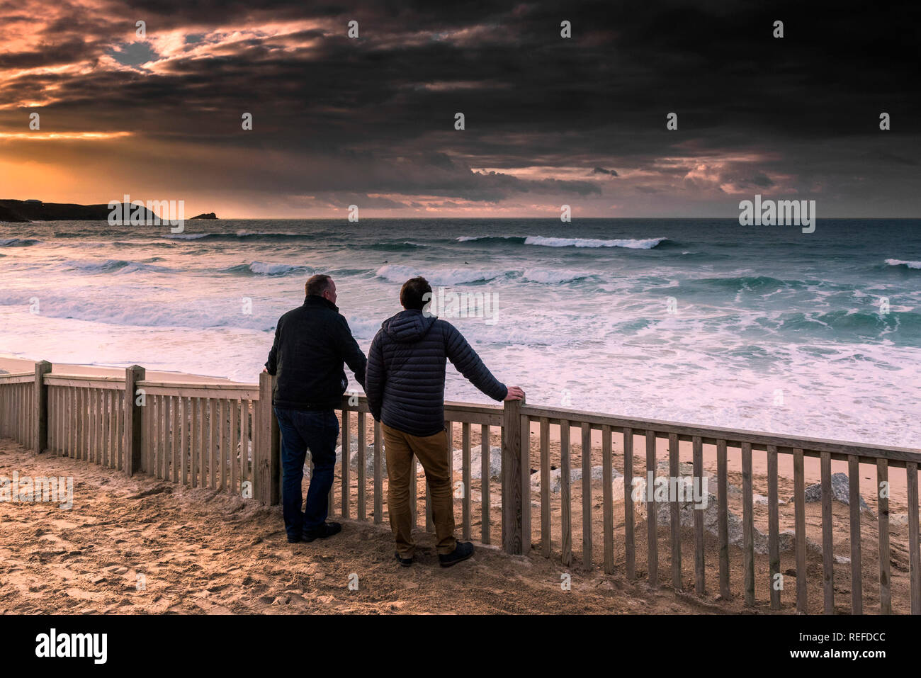 Two people watching a spectacular sunset as storm clouds build over ...