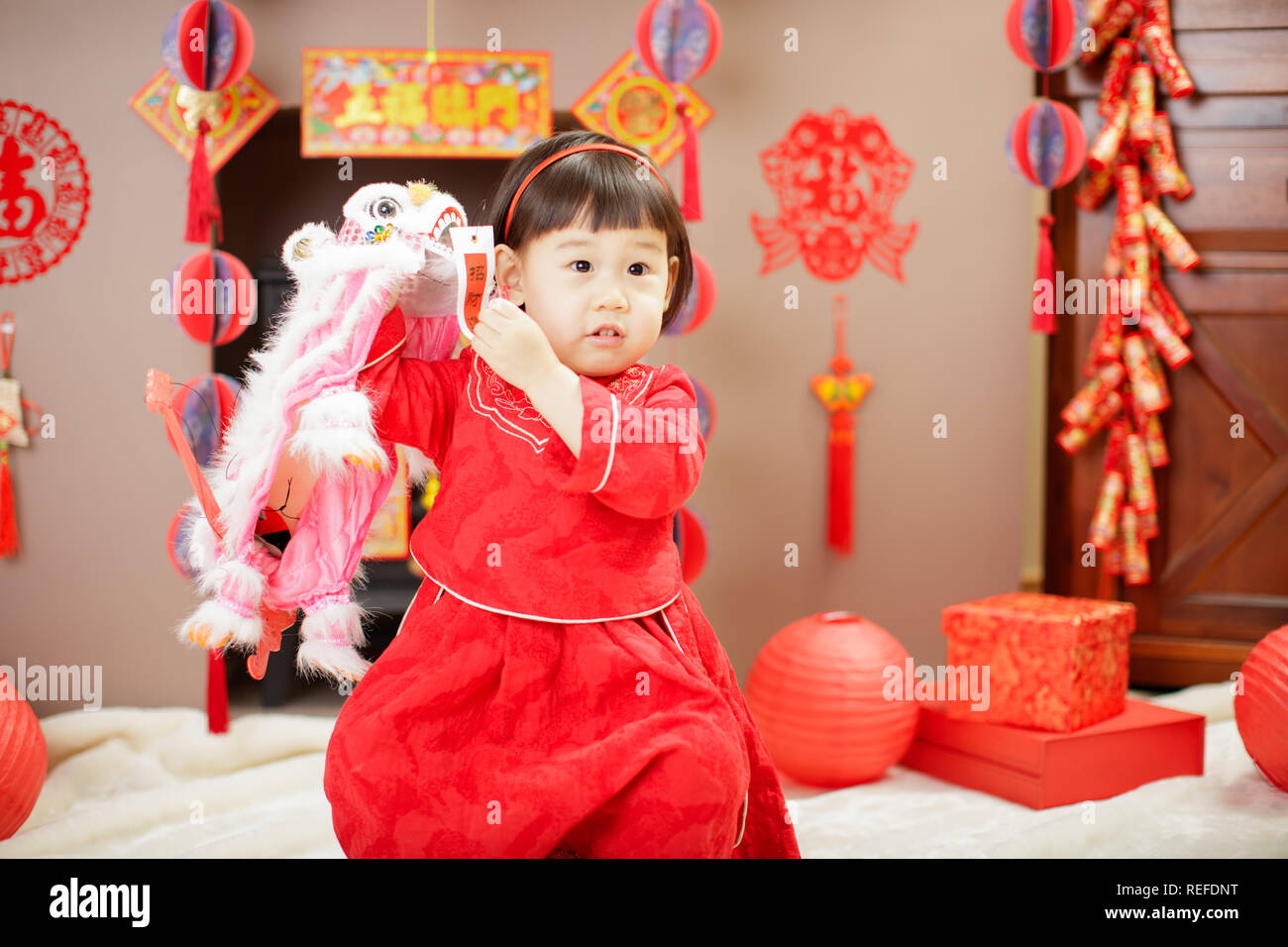 Chinese baby girl traditional dressing up holding a dance loin toy with ...
