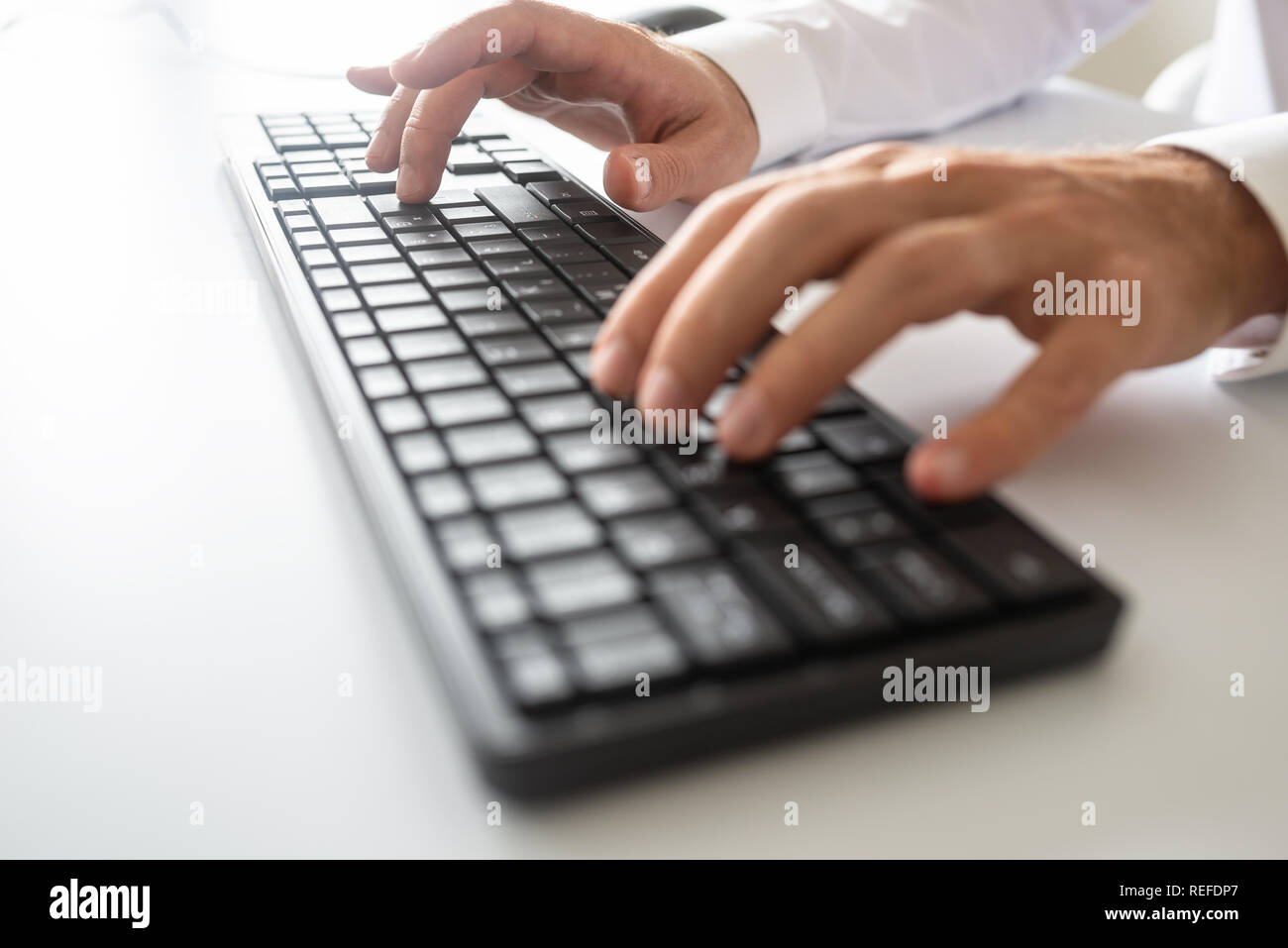 Closeup view of male hands using black computer keyboard typing an ...