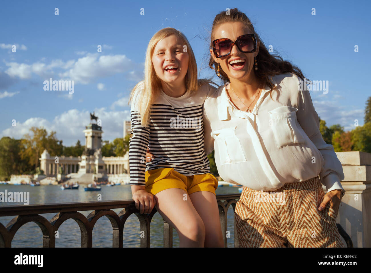 Portrait of happy trendy mother and child tourists at El Retiro Park in ...