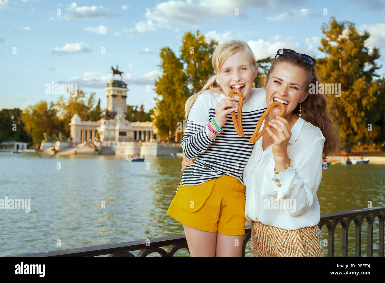 smiling modern mother and daughter tourists at Retiro Park in Madrid ...