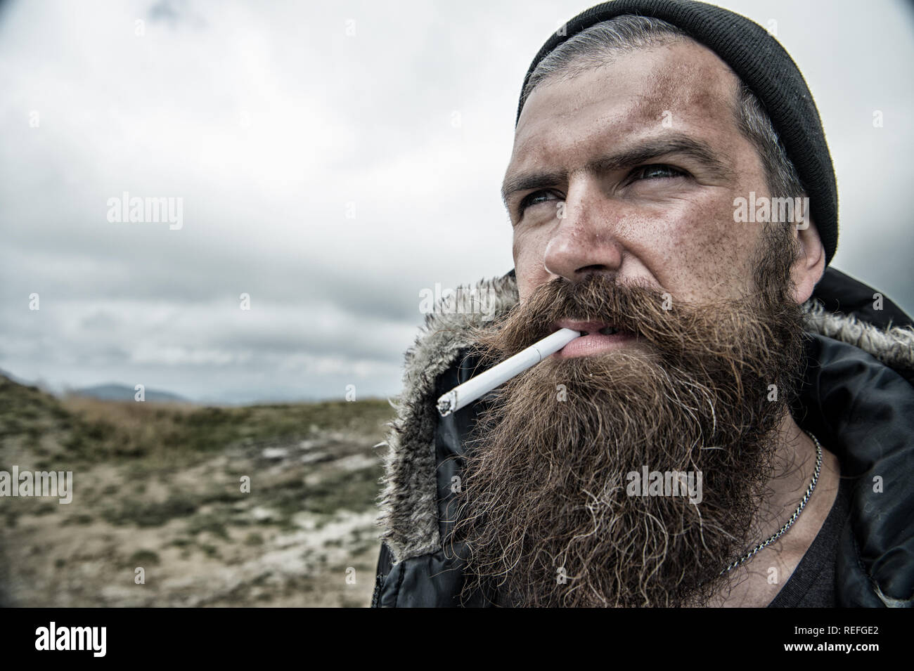 Man with long beard and mustache smoking cigaret. Brutality concept ...