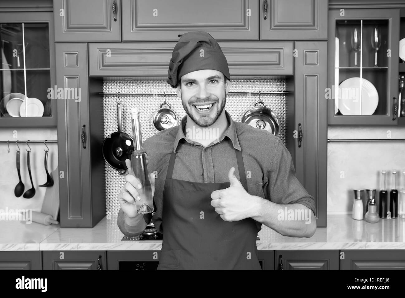 Happy man chef show thumbs up with olive oil bottle in kitchen. Food ...