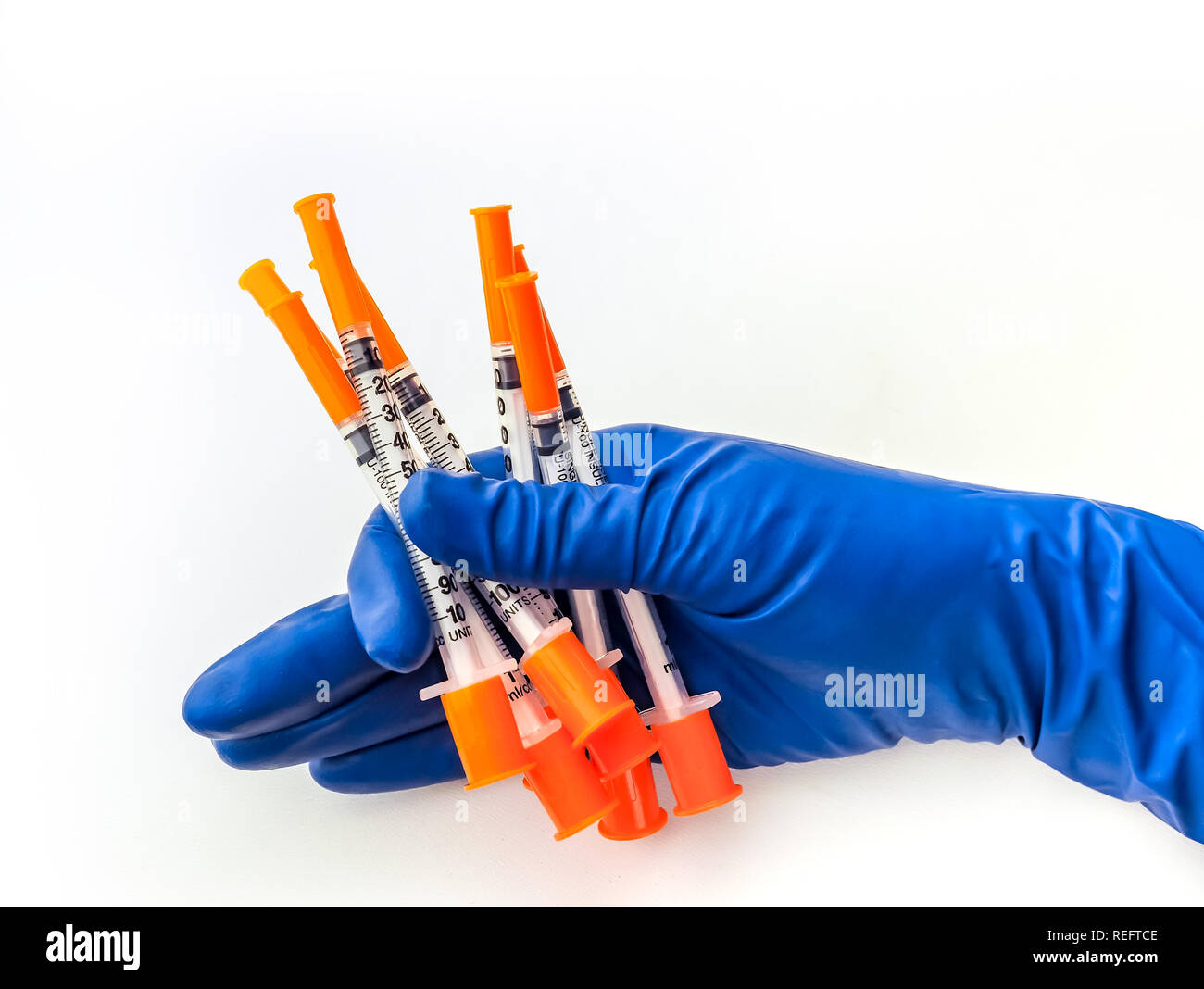 Doctor's hand in blue medical glove holding several syringes with ...