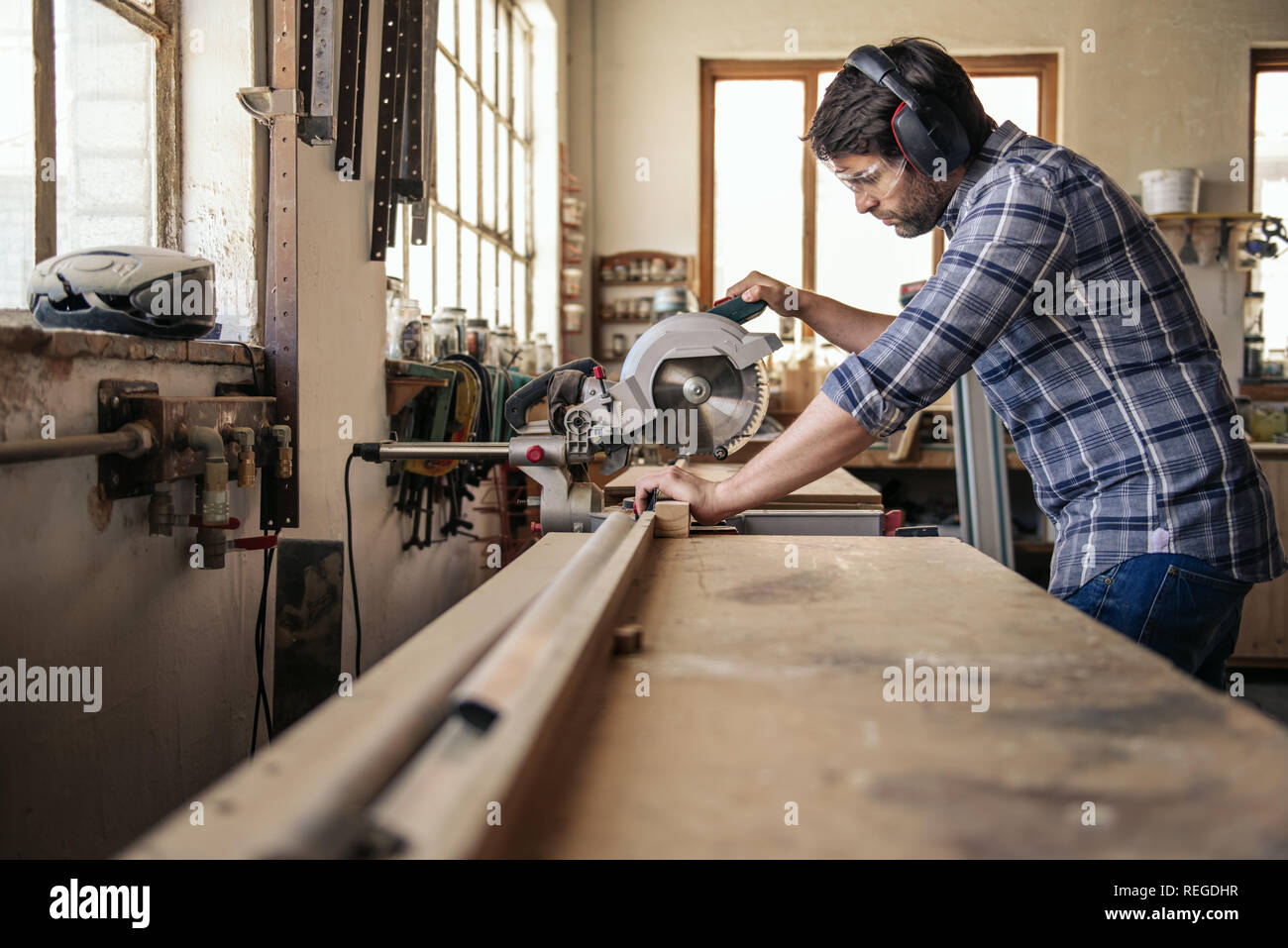 Carpenter cutting wood with a mitre saw in his workshop Stock Photo - Alamy