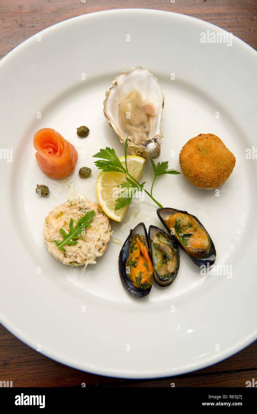 A starter of smoked salmon, oyster, crab croquette, mussels and ...