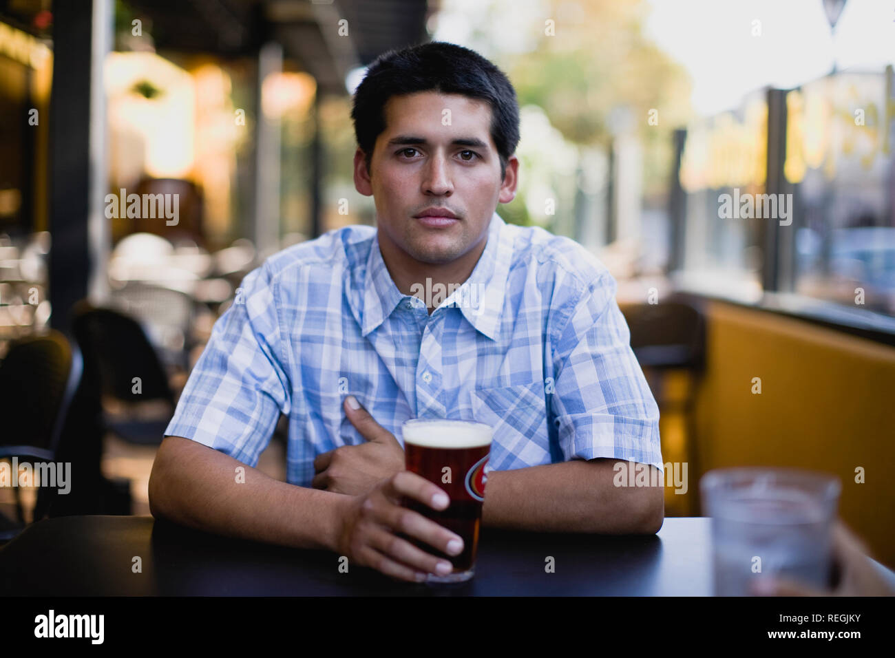 Portrait of a young adult man sitting at a bar having a beer Stock ...
