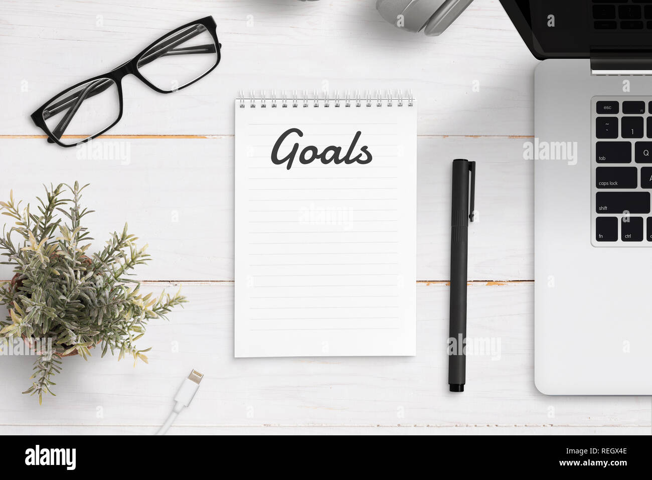 Writing annual goals on empty notepad. Office desk with laptop computer ...