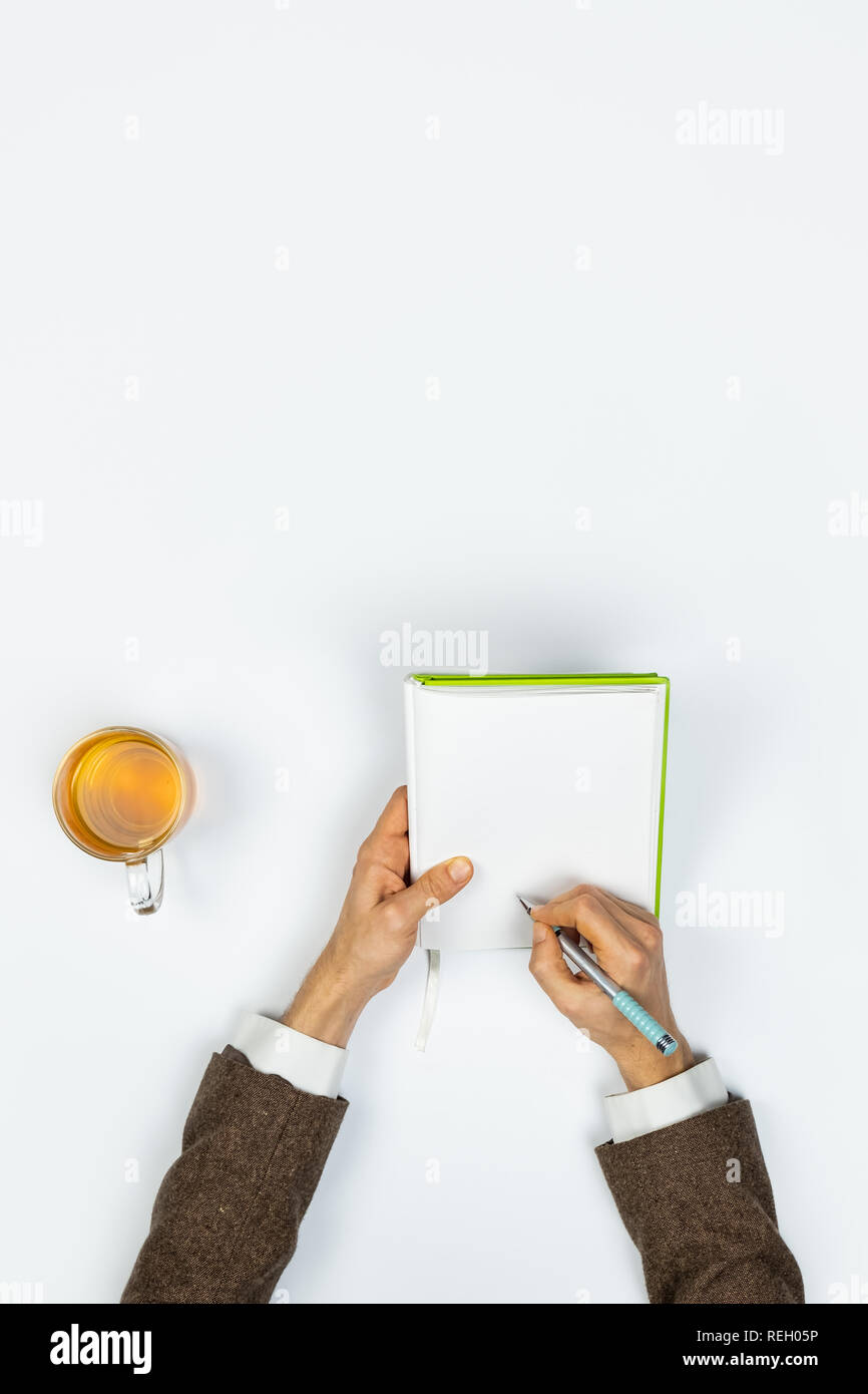 Writing in a note pad, top view. Male person's hands taking notes in a ...