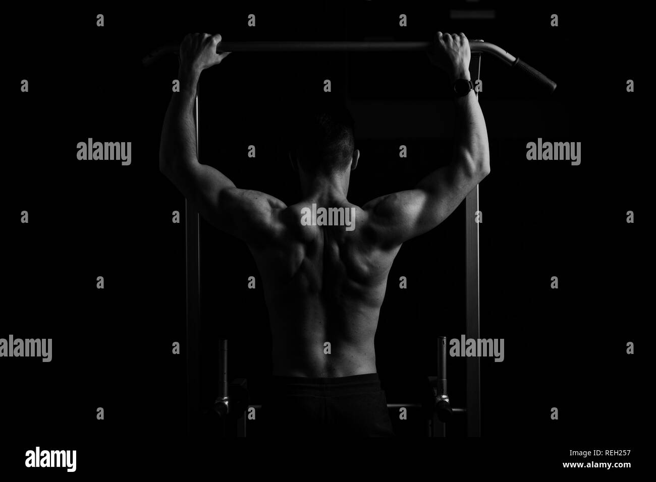 Power muscular bodybuilder guy doing pullups in gym black and white ...