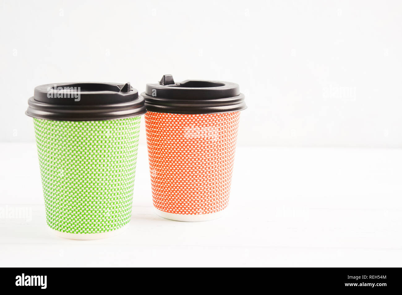 Green and red eco paper cups on white background with copy space ...