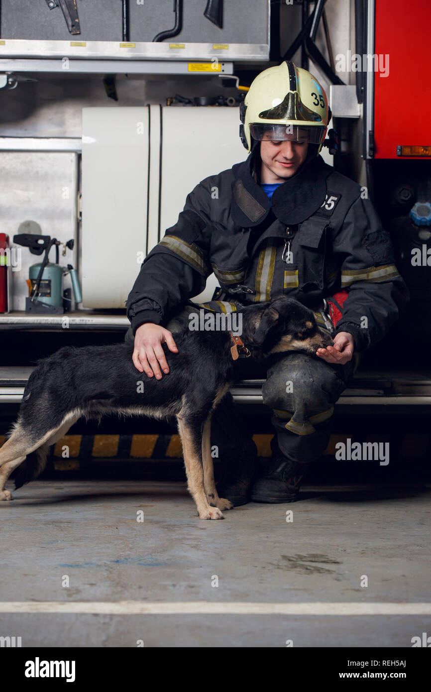 Image of happy fireman in helmet with dog Stock Photo - Alamy