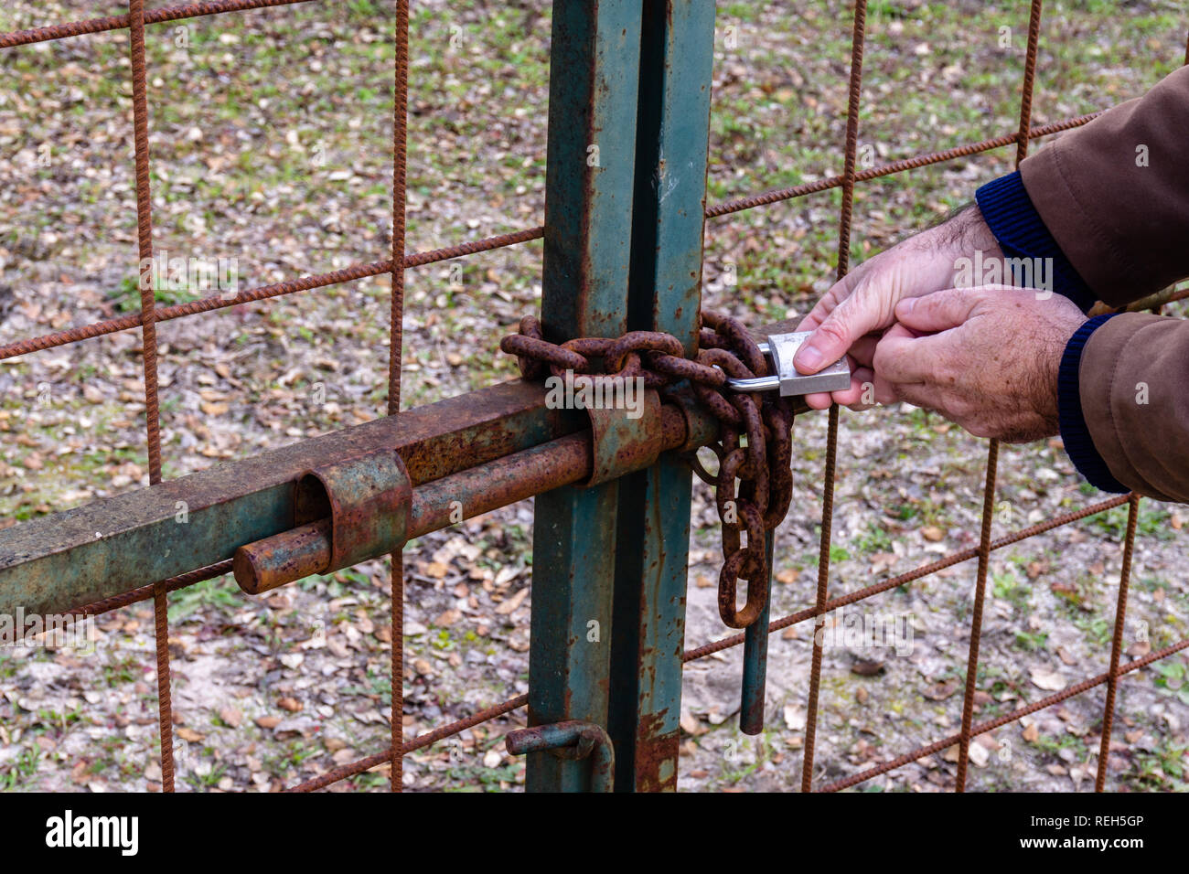 Unlocking padlock on the gate of rusty metal steel Stock Photo - Alamy