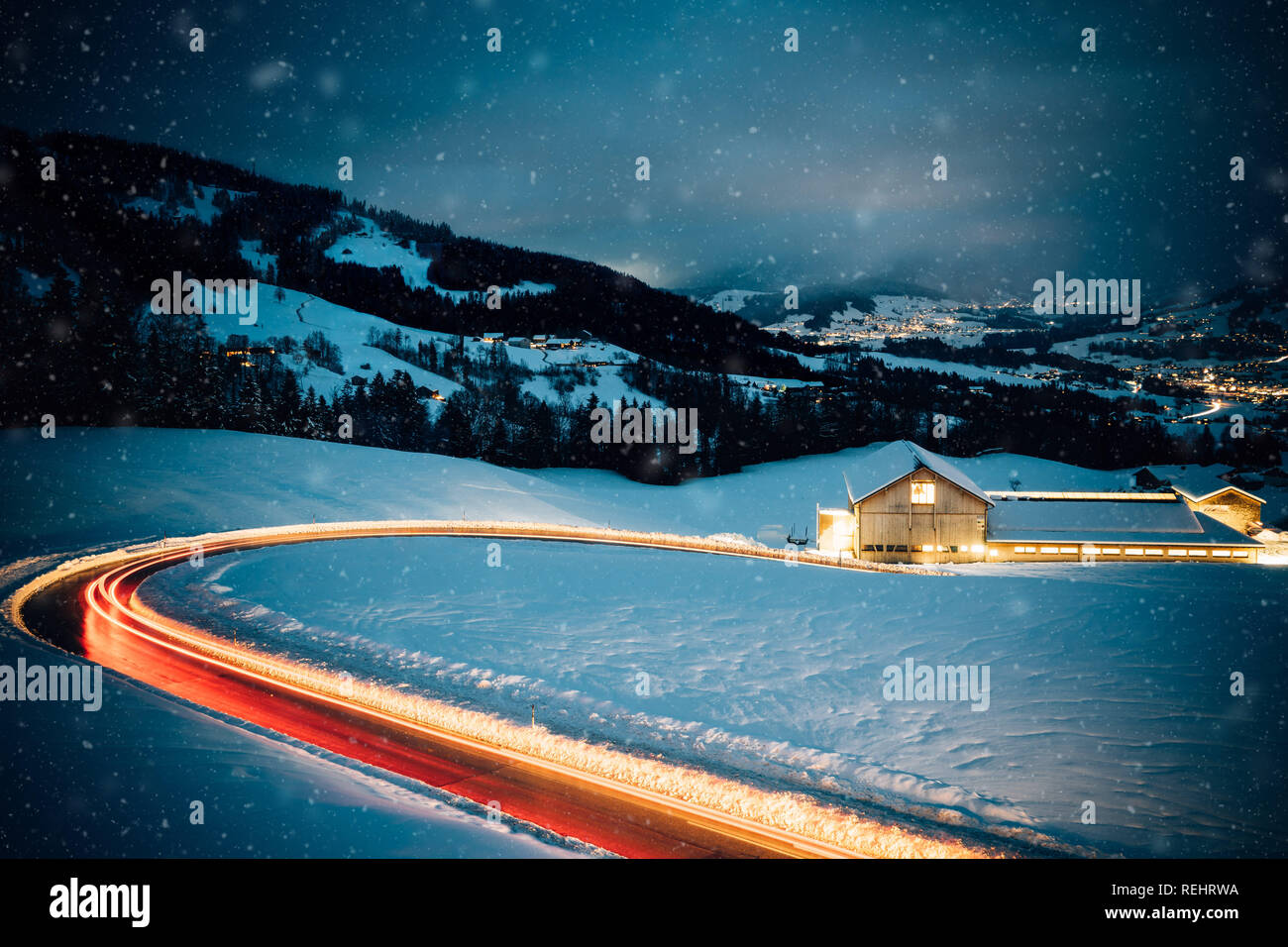 Long exposed night photography of cars driving through a snowy mountain ...