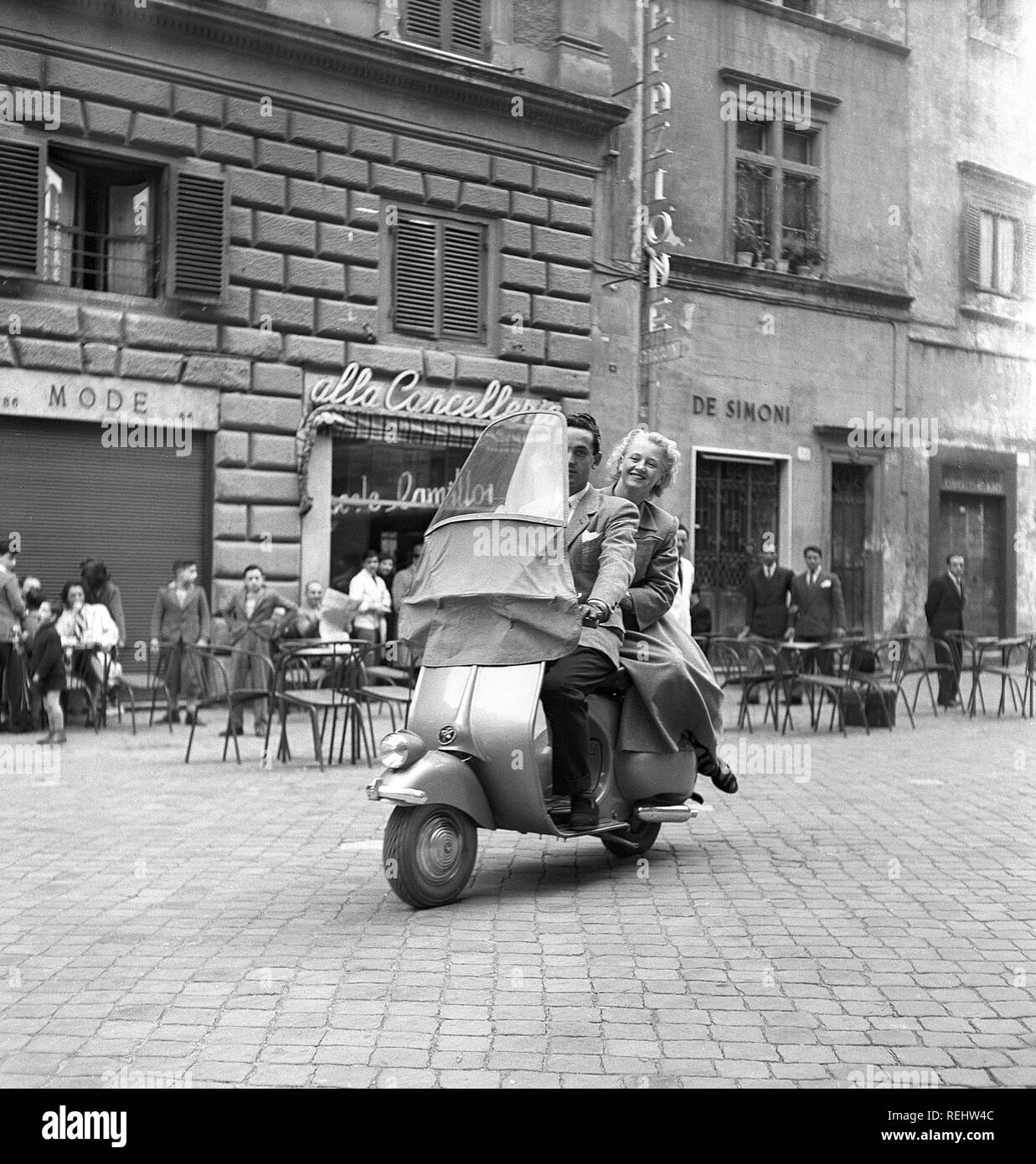 Couple in Italy in the 1950s. A young couple on a Vespa scooter driving ...