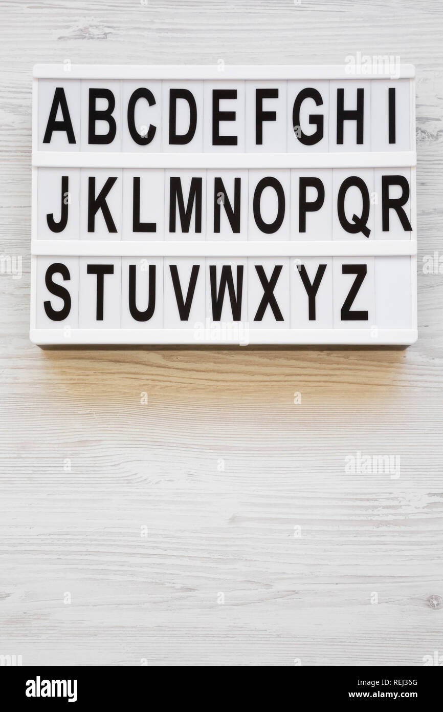 English alphabet on modern board over white wooden surface, top view ...