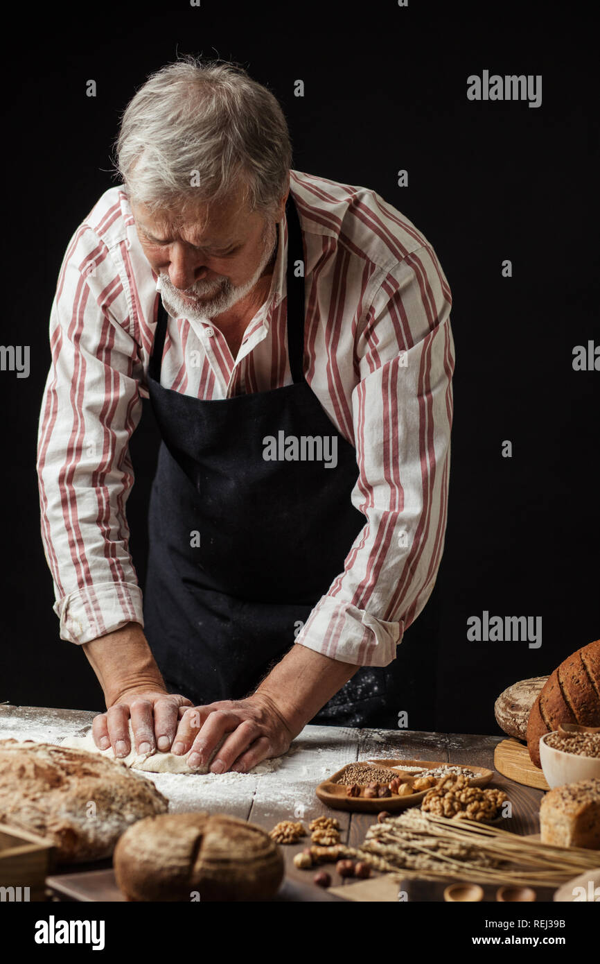 Mature bearded baker man kneading dough for bread on table Stock Photo ...
