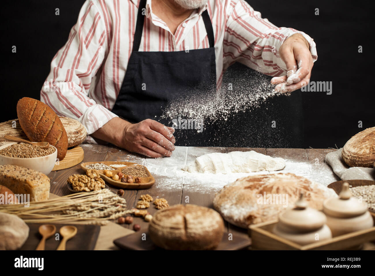 Man sprinkling some flour on dough. Hands kneading dough, cropped view ...