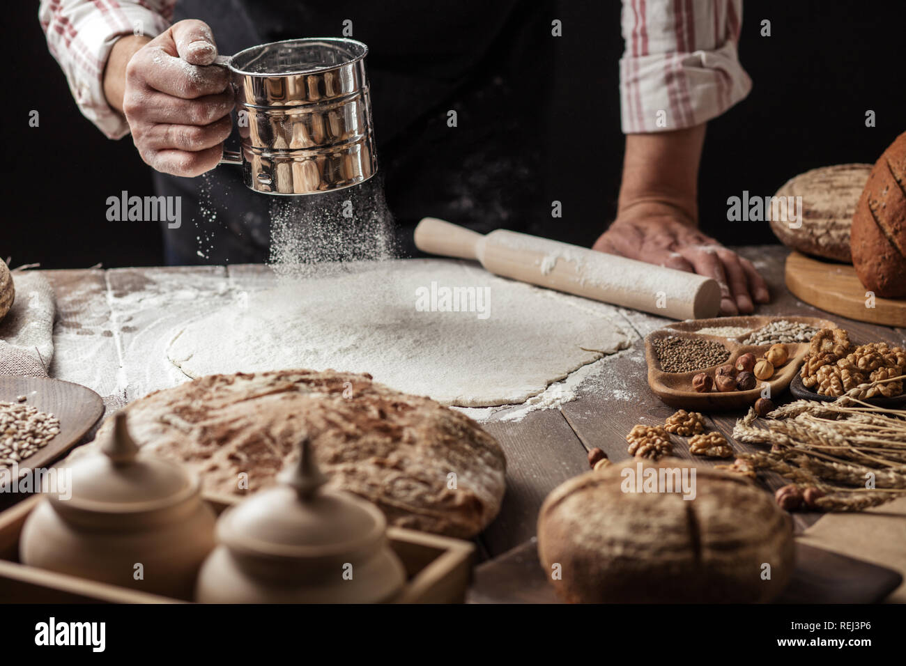 Man sprinkling some flour on dough. Hands kneading dough, cropped view ...