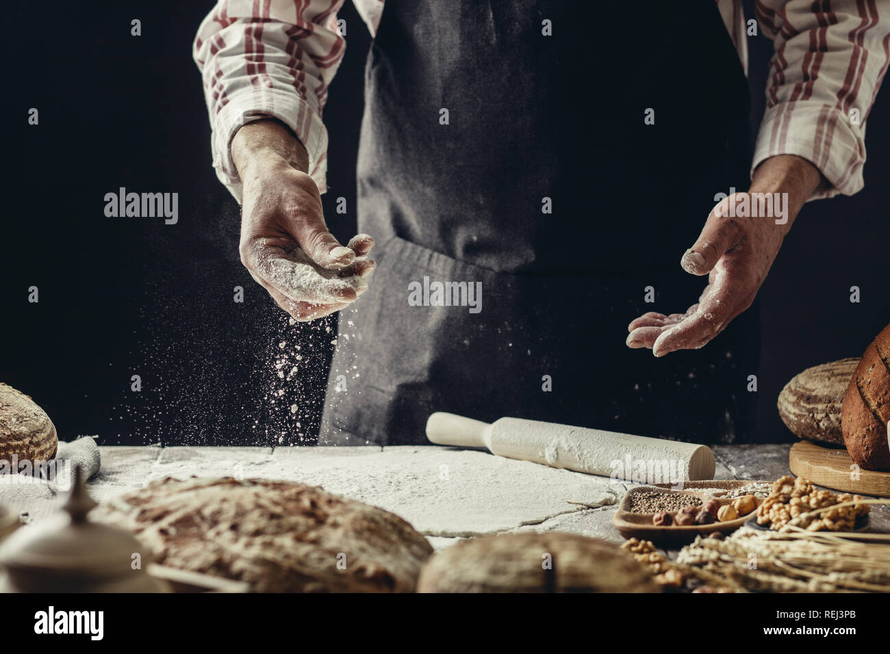 Man sprinkling some flour on dough. Hands kneading dough, cropped view ...