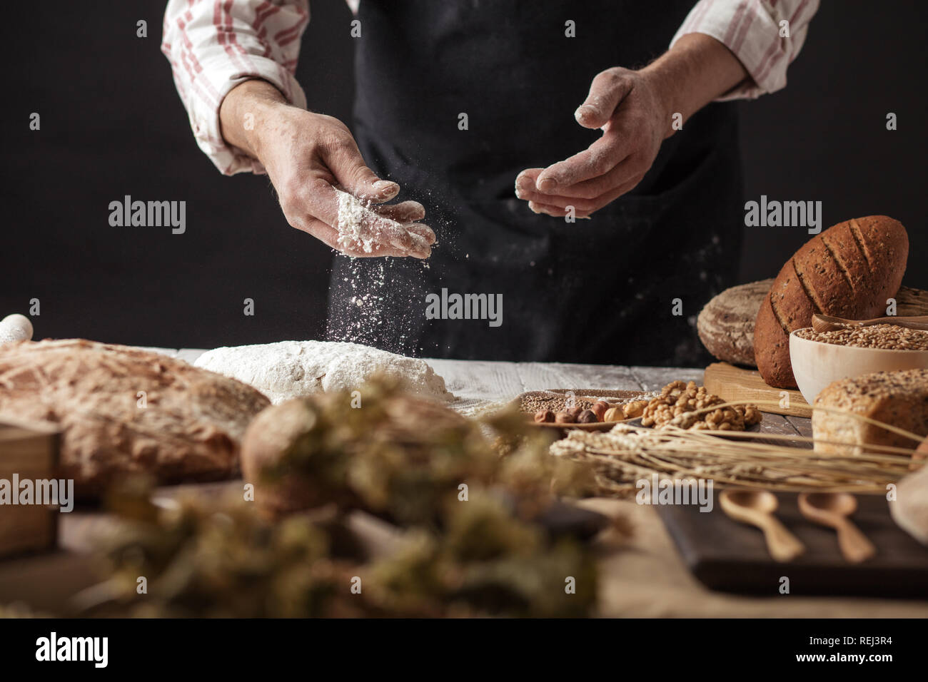 Man sprinkling some flour on dough. Hands kneading dough, cropped view ...