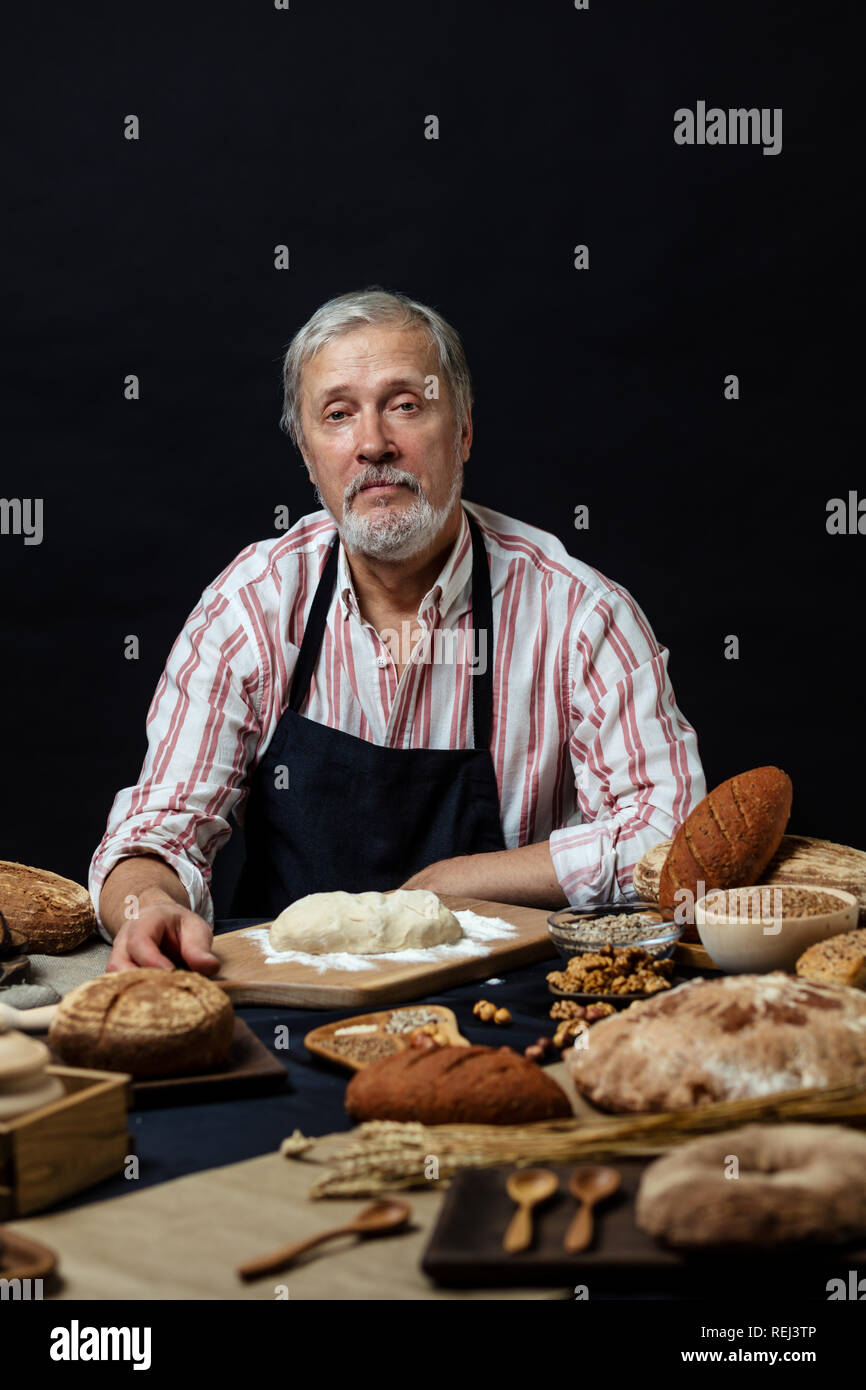 Elderly smiling professional chef man. Isolated over black background ...